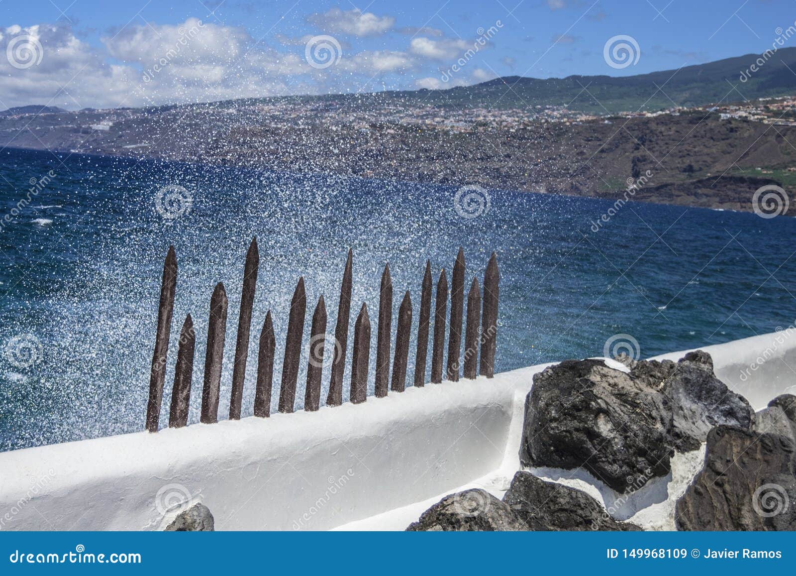 Splash of the Ocean on a Fence with a Nice Village in the Background ...