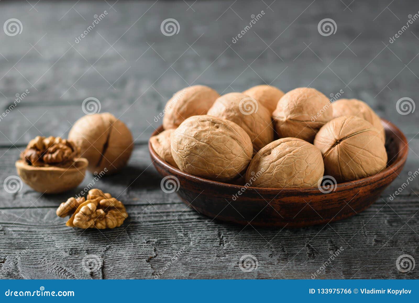 Split Walnut with a Clay Bowl Full of Nuts on a Dark Rustic Table Stock ...