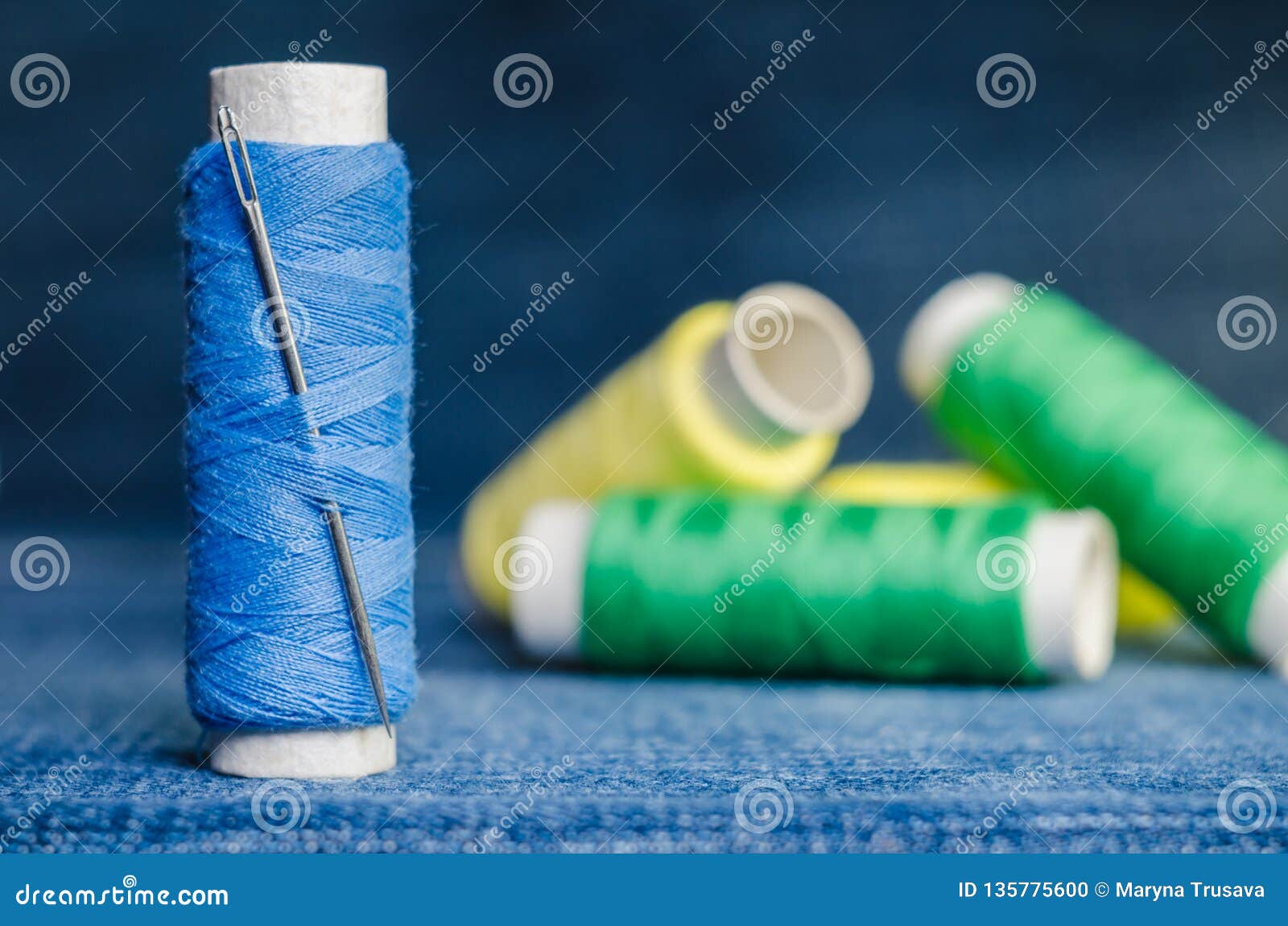 Spool of Blue Thread with a Needle on the Background of Spools of Green ...