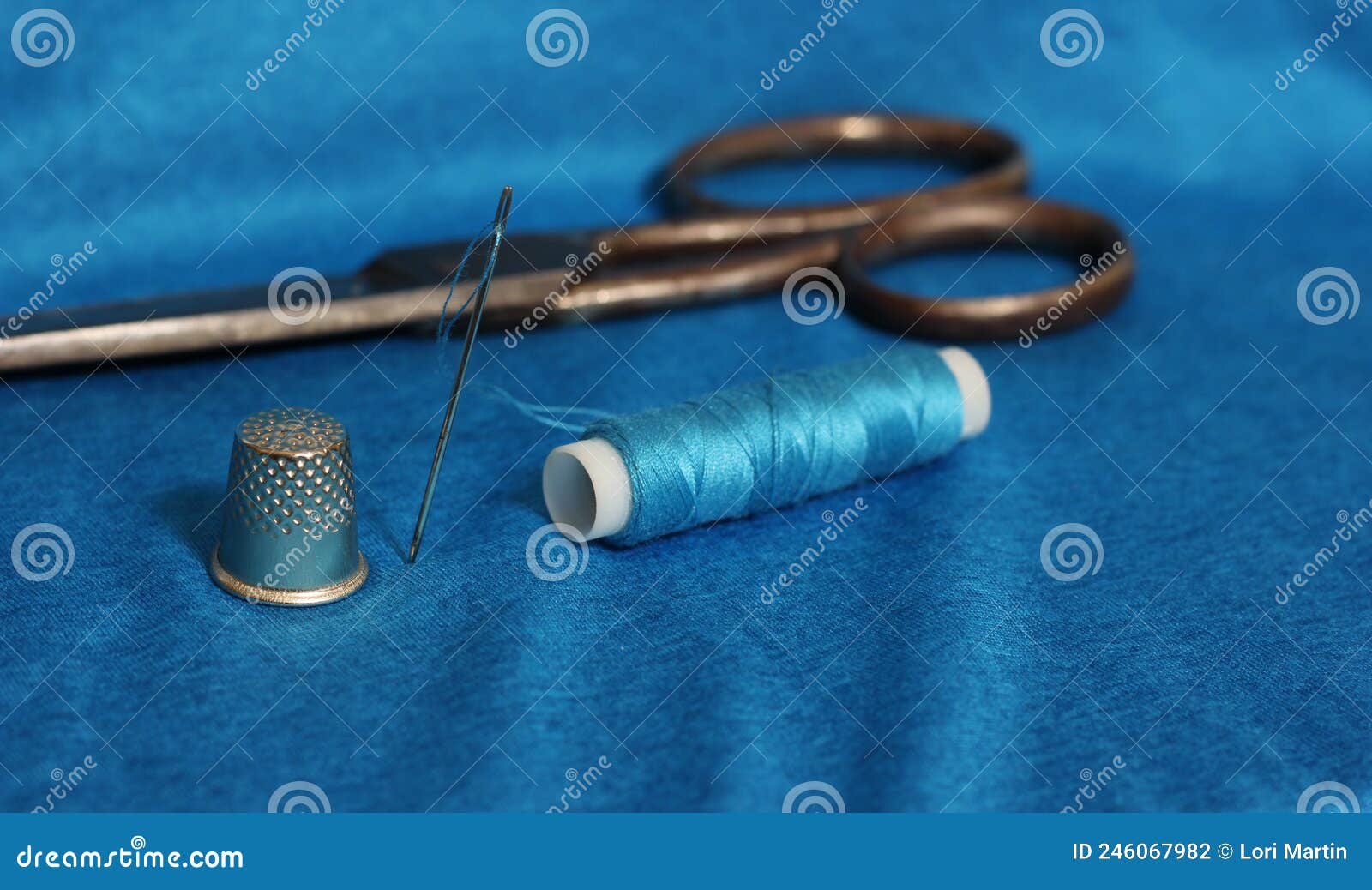 Spool of Blue Thread, Thimble and Needle on Blue Fabric Stock Photo ...