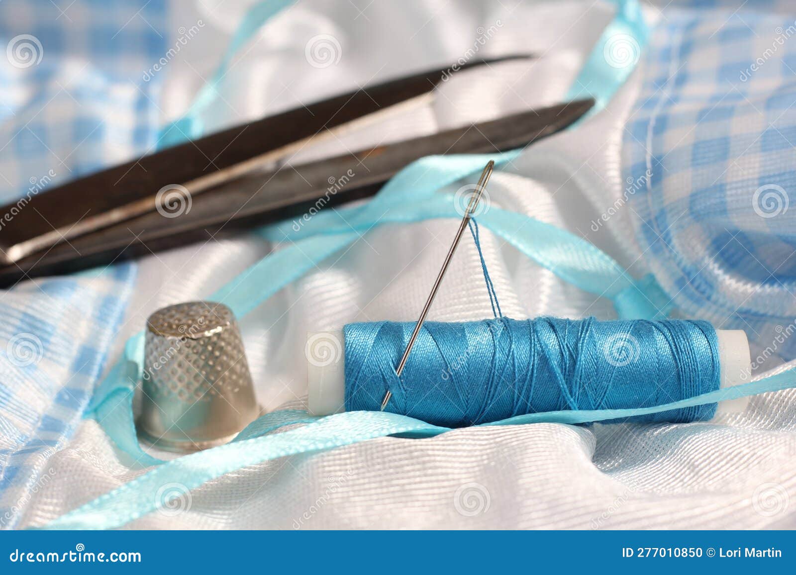 Spool of Blue Thread, Thimble and Needle on Blue and White Fabric Stock ...