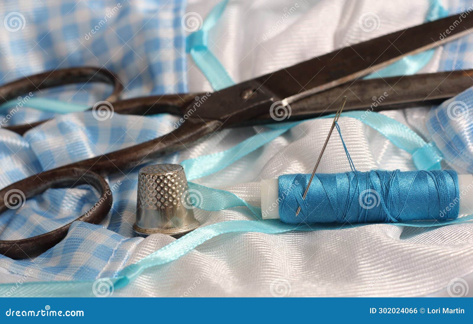 Spool of Blue Thread, Thimble and Needle on Blue and White Fabric Stock ...