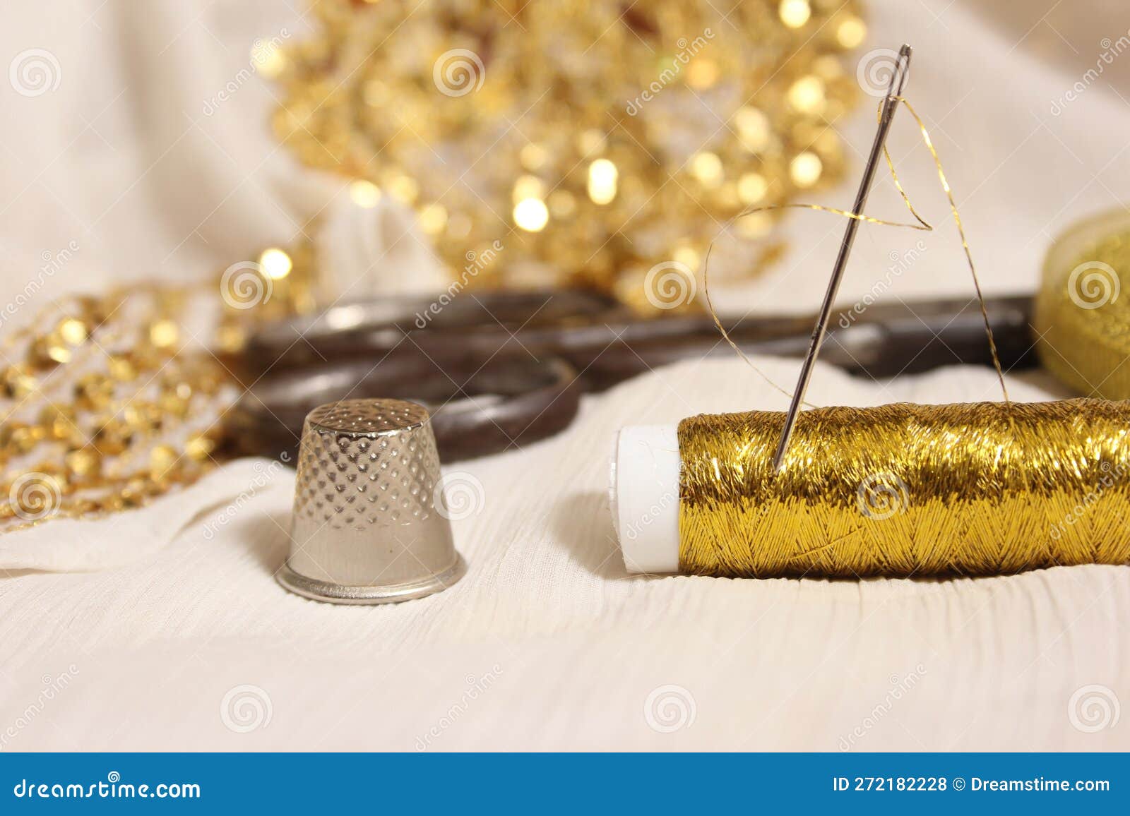 Spool of Gold Thread and Scissors with Thimble on Off White Fabric with ...