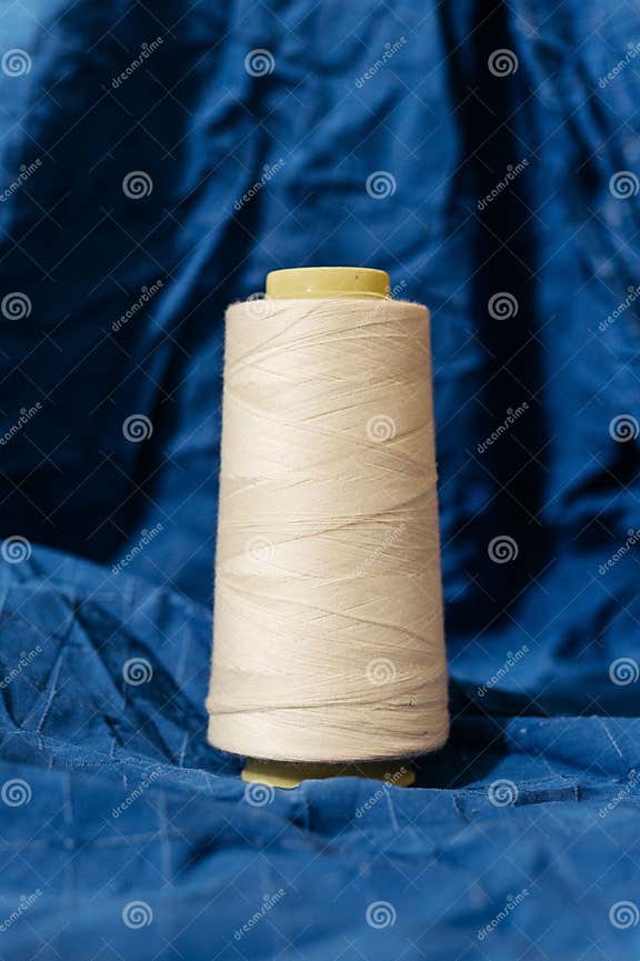 Spool of Ivory Thread Sitting on a Solid Navy Blue Fabric Surface Stock ...