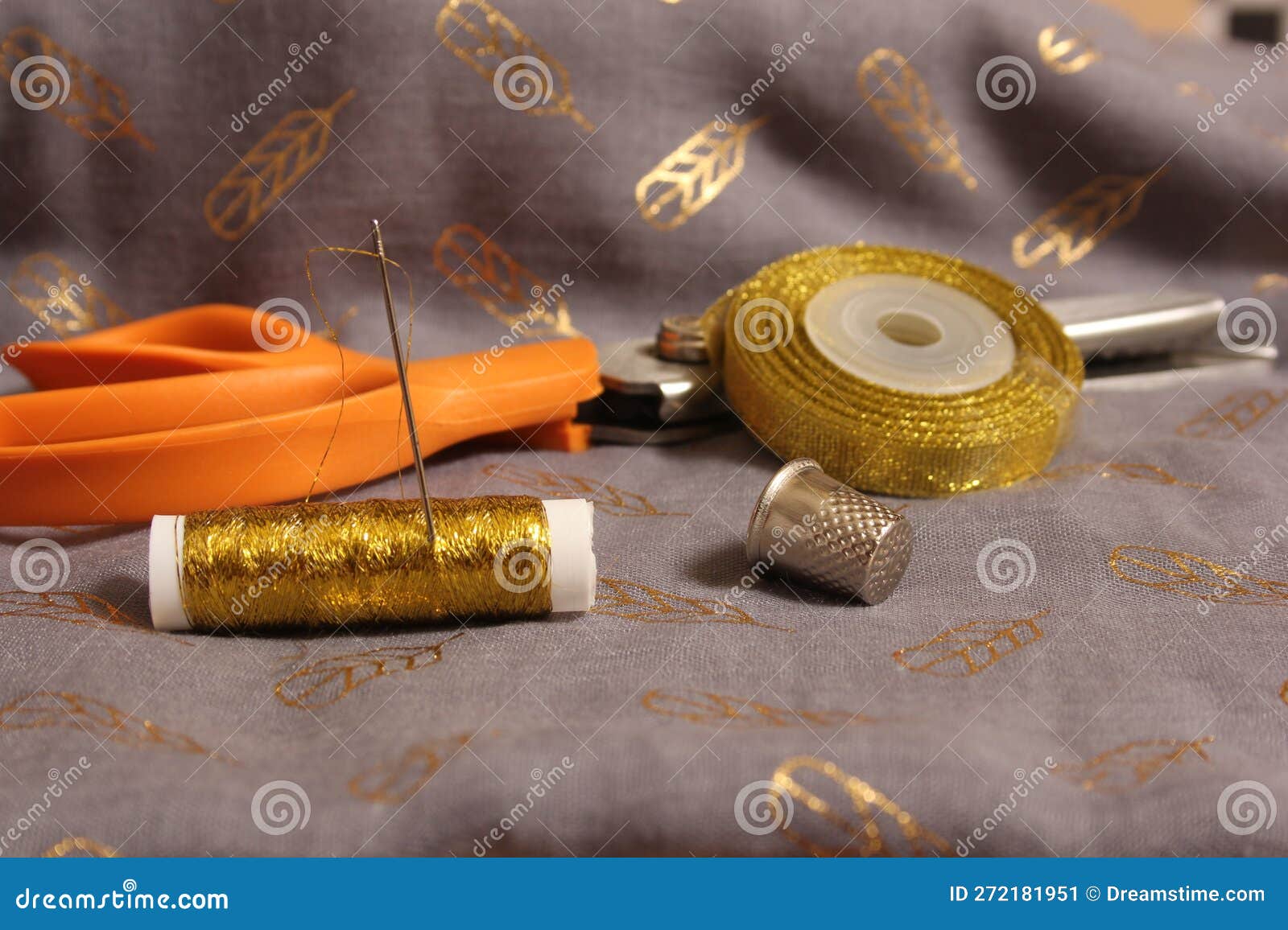 Spool of Metallic Gold Thread on Gray and Gold Chiffon Fabric Stock ...