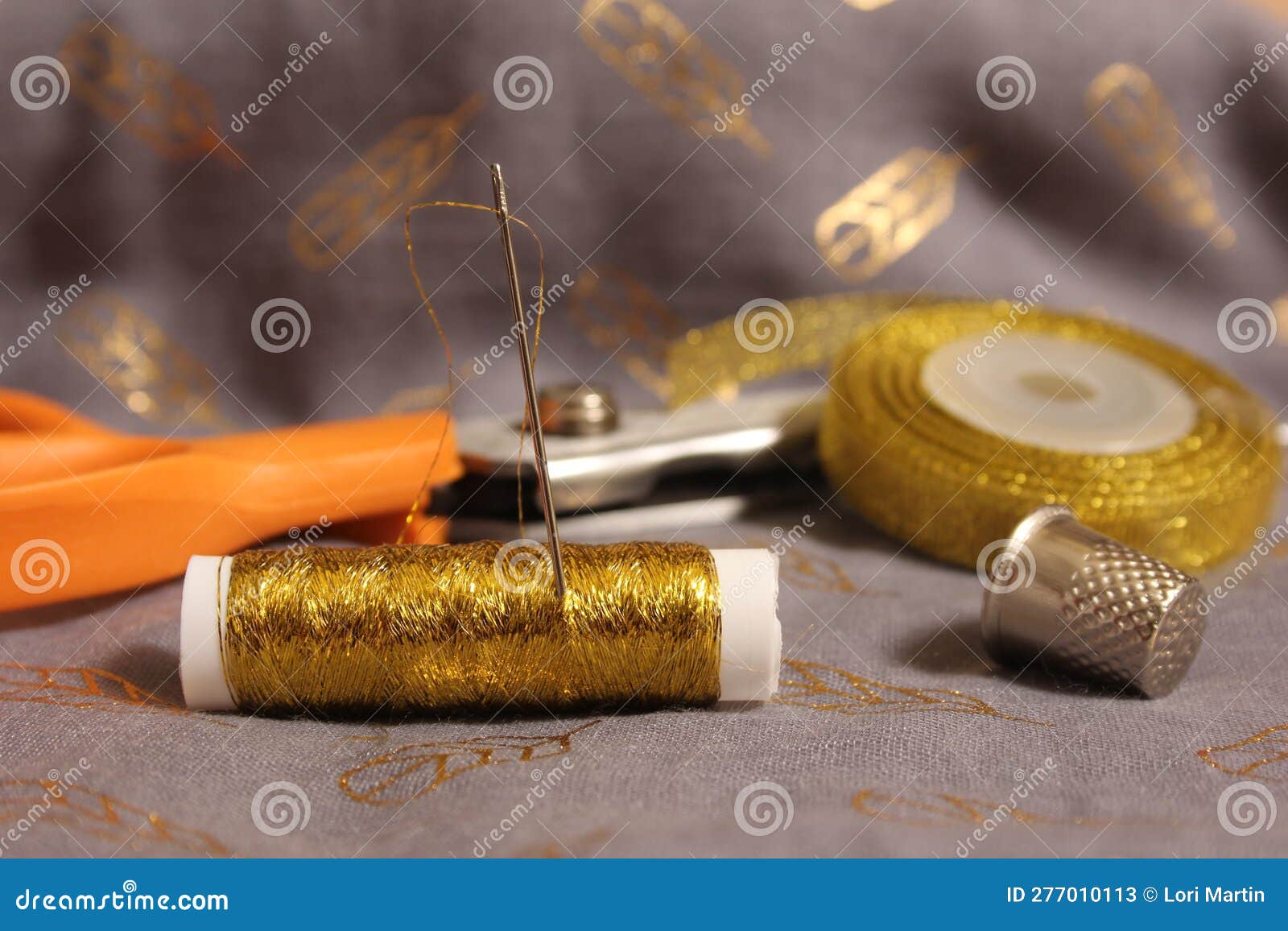 Spool of Metallic Gold Thread on Gray and Gold Chiffon Fabric Stock ...