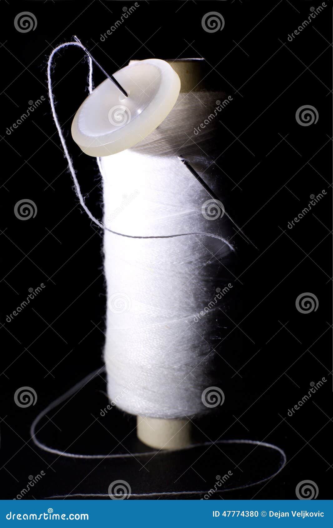 Spool of White Thread with Needle and White Button on Black Background ...