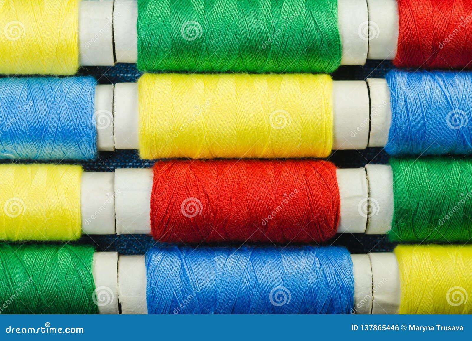 Spools of Blue, Yellow, Red and Green Sewing Thread Arranged in Rows on ...