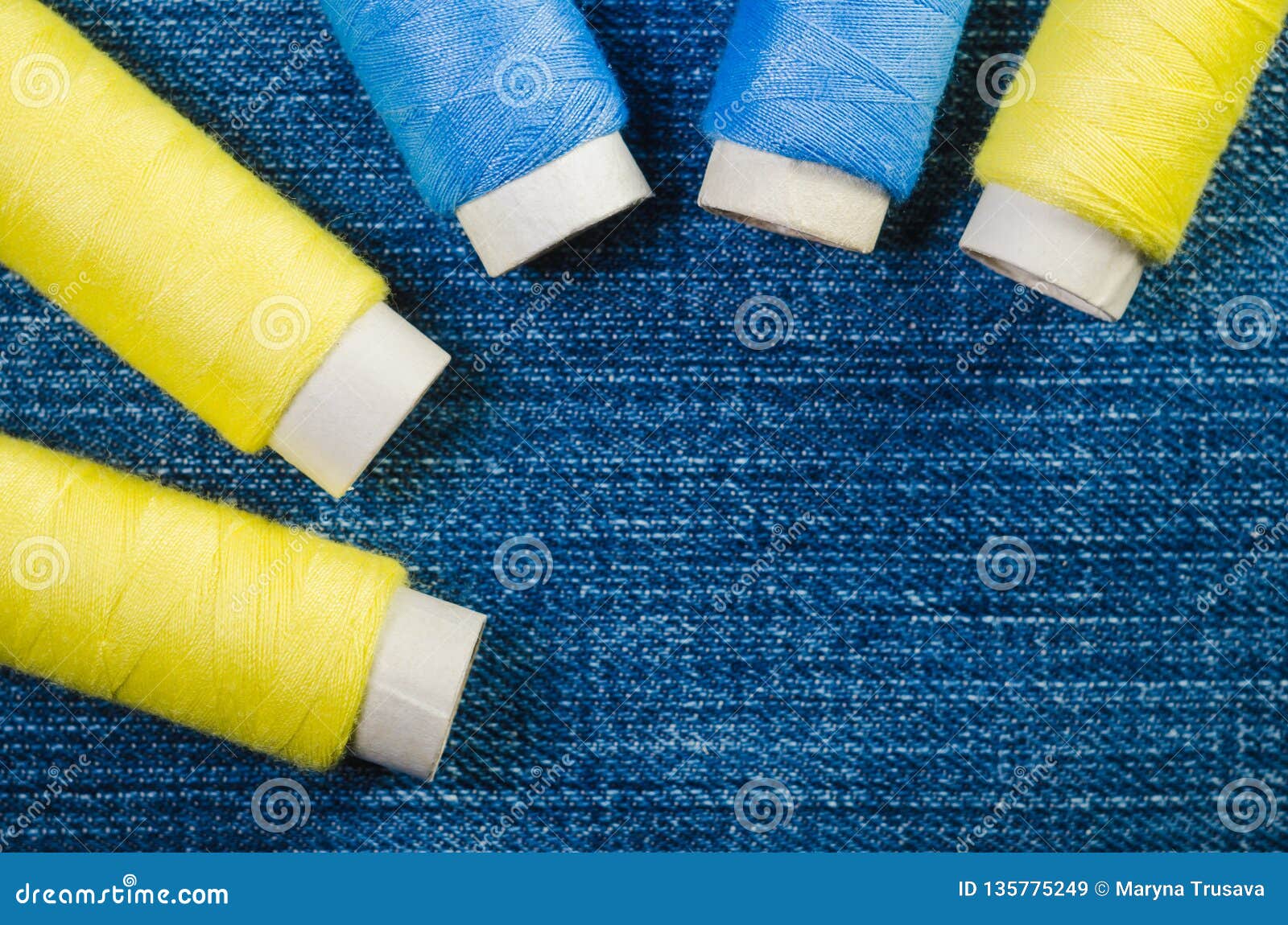 Spools of Blue and Yellow Threads Arranged in a Semicircle on Denim ...