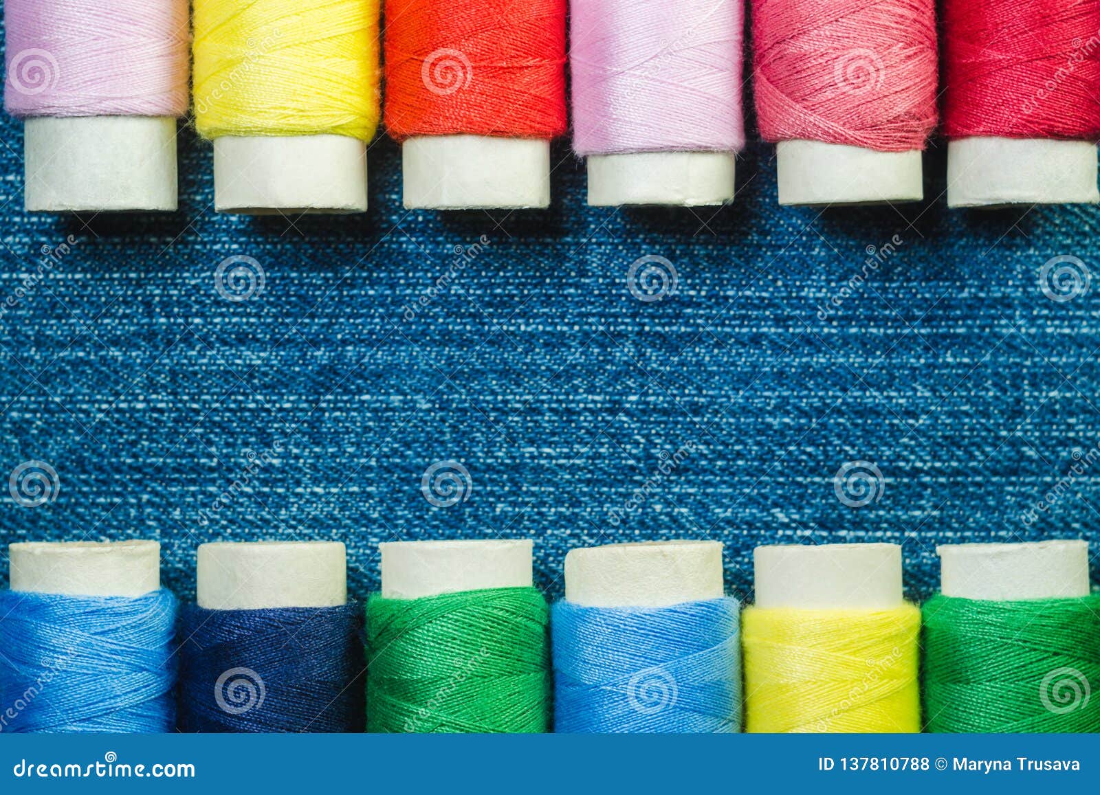 Spools of Colored Sewing Thread Arranged in Two Rows on Denim with Copy ...
