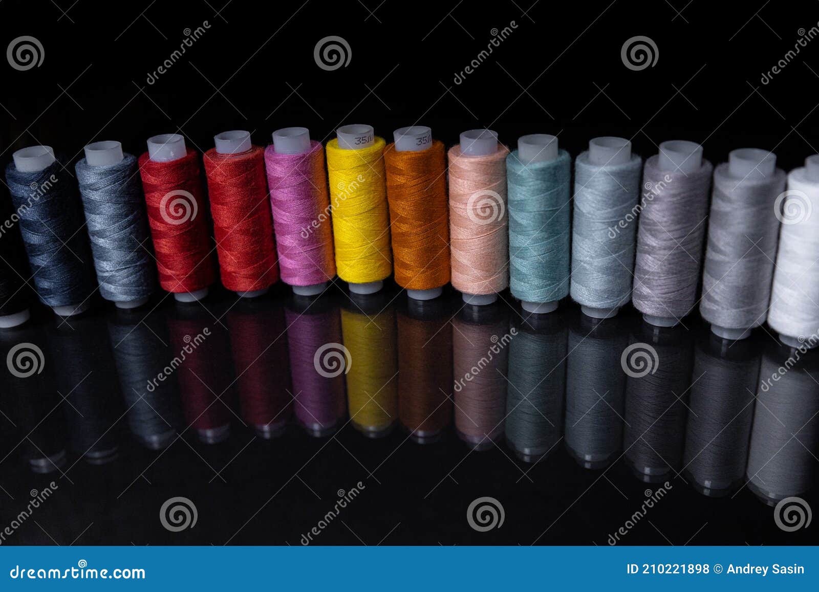 Spools with Multi-colored Threads Stand in a Row on a Mirror Surface ...