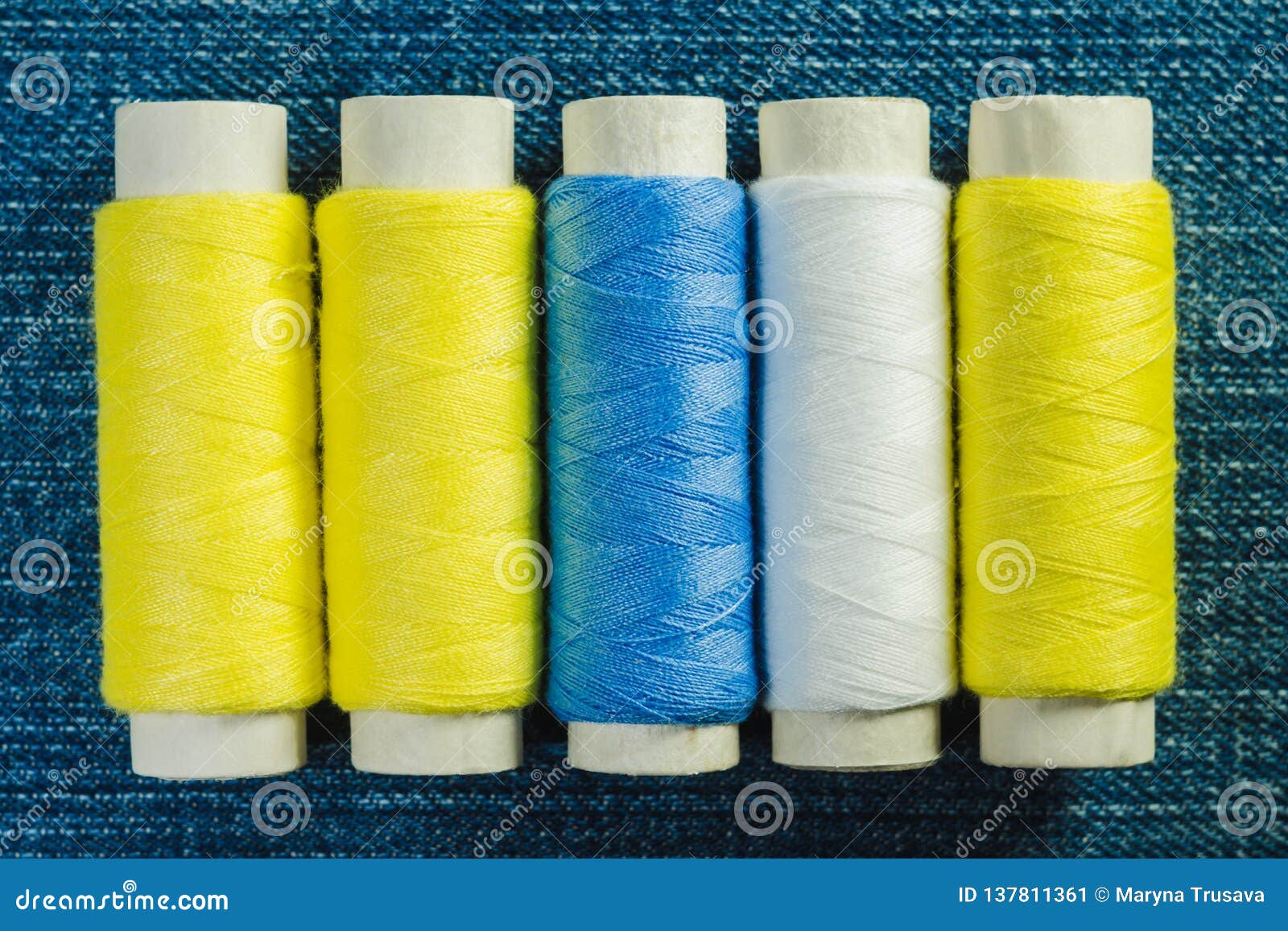 Spools of White, Yellow and Green Sewing Thread Arranged in Row on ...