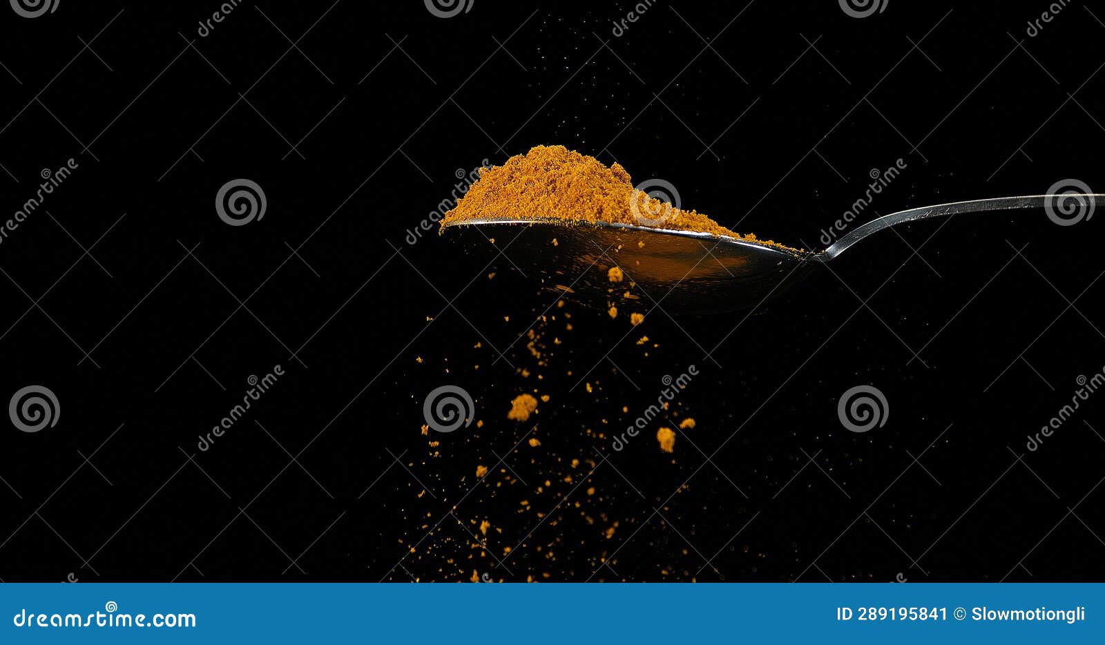 Spoon and Curry Powder Falling from Spoon Against Black Background ...