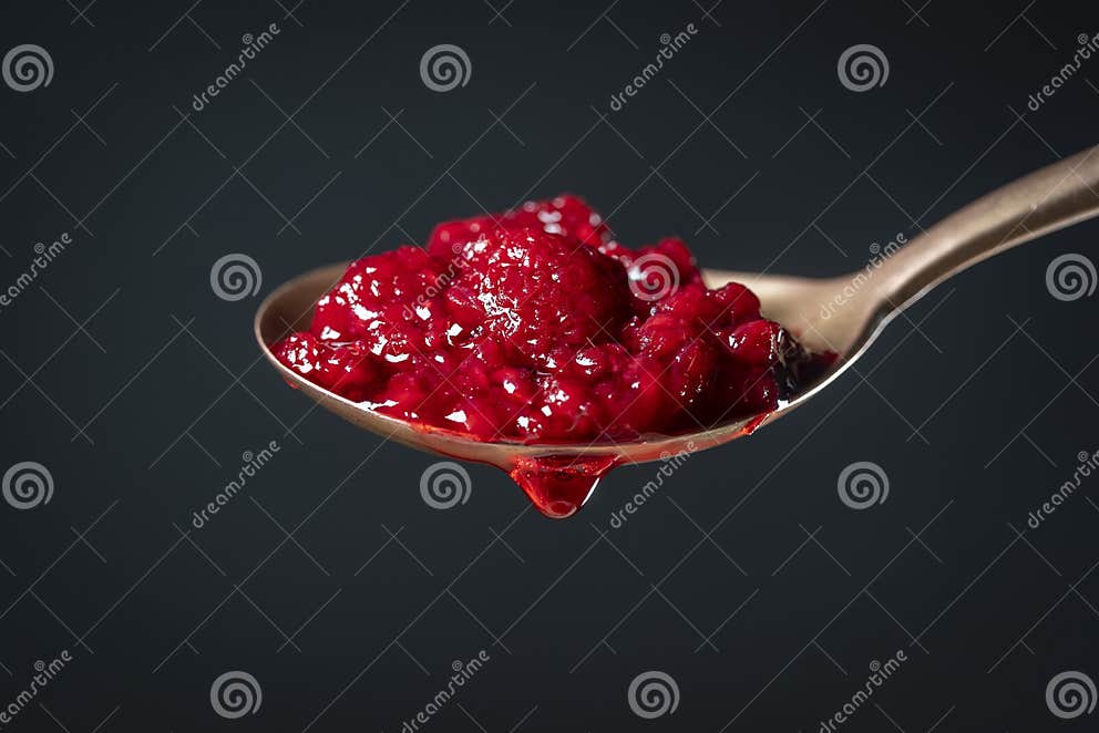 Thick Red Raspberry Jam Dripping from the Spoon, One Drop, on Black ...