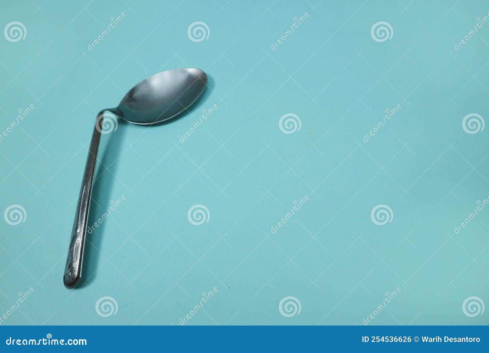 A Used and Bent Spoon, Isolated on a Blue Background. Stock Photo ...