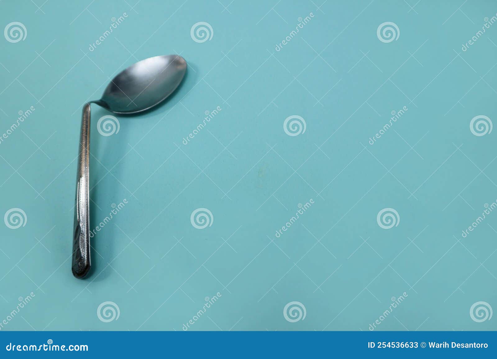 A Used and Bent Spoon, Isolated on a Blue Background. Stock Image ...
