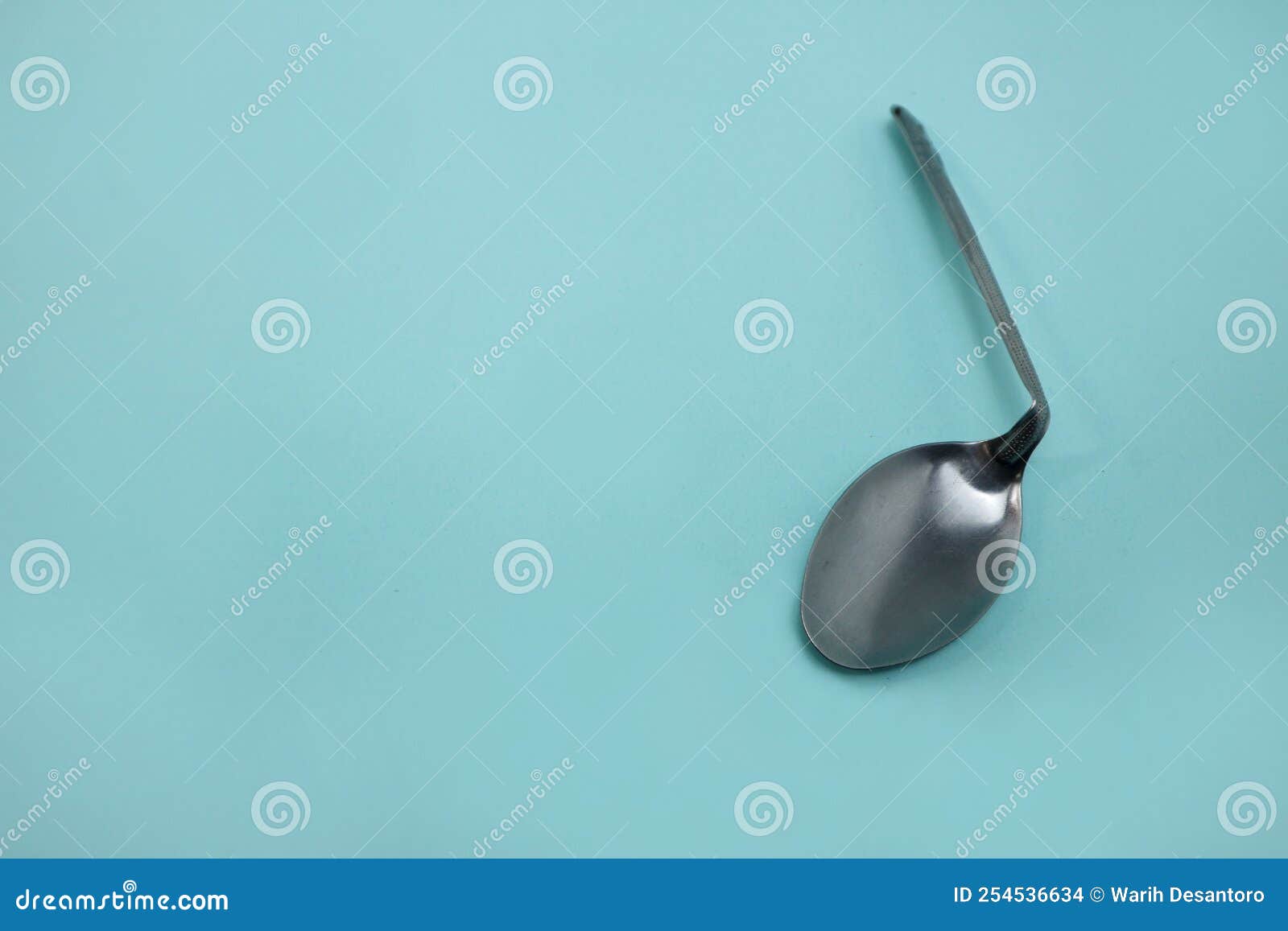 A Used and Bent Spoon, Isolated on a Blue Background. Stock Photo ...