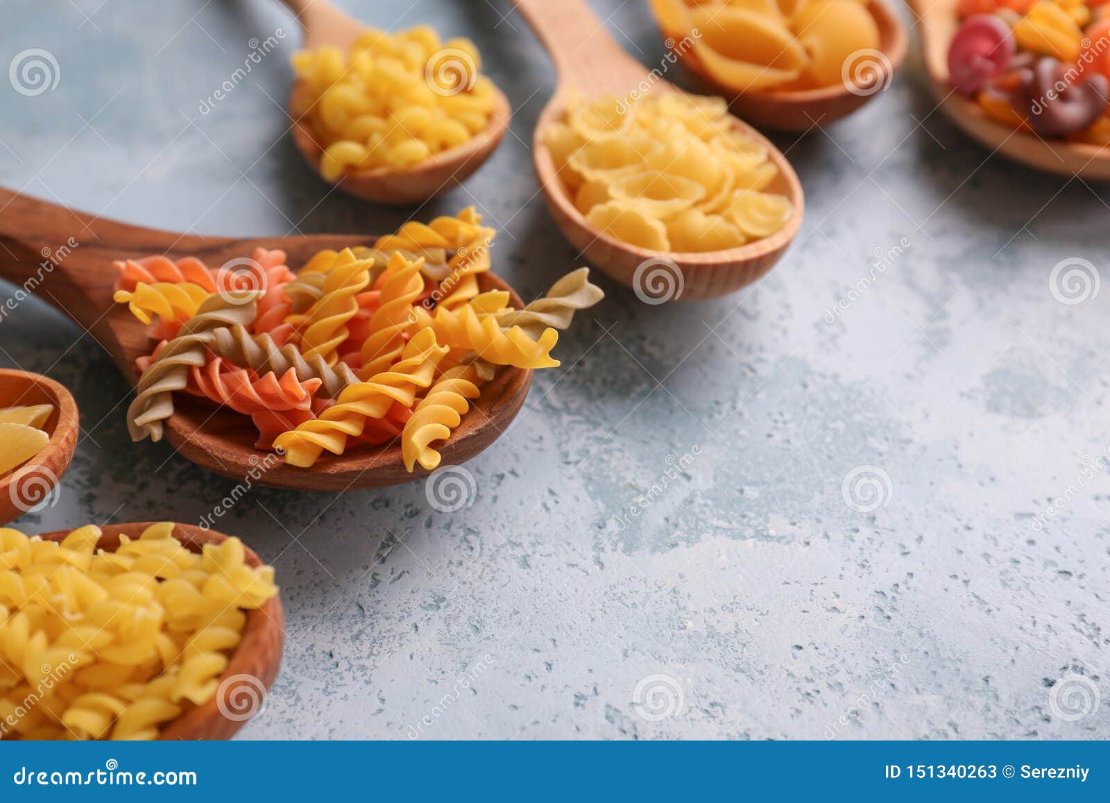 Spoons with Different Types of Raw Pasta on Color Table Stock Image ...