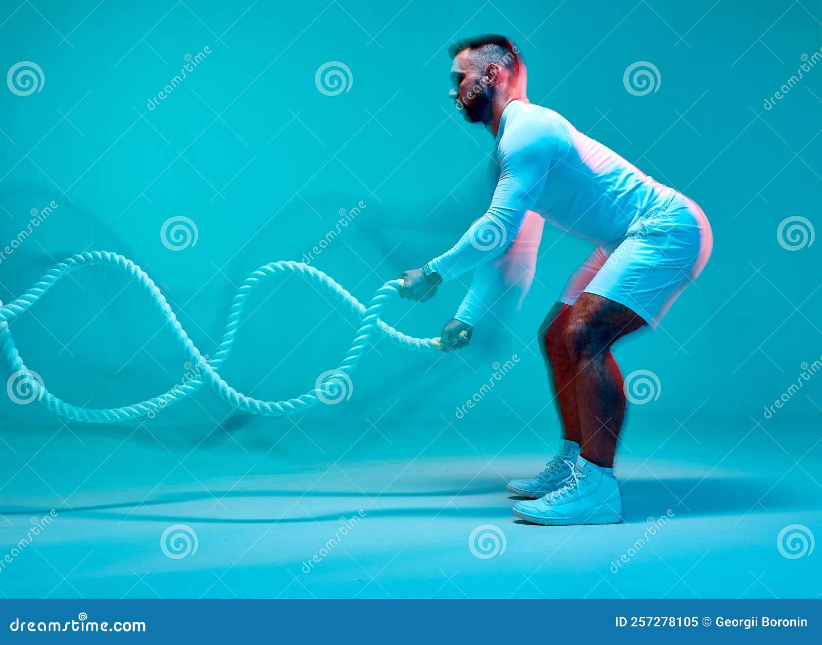 Sportive Modern Guy Training Makes Exercise with Ropes on Blue Studio ...