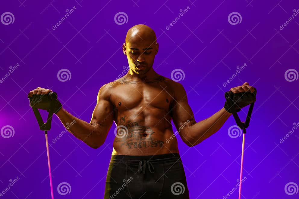 Sporty Man Performs Exercises with Expander on Violet Studio Background ...