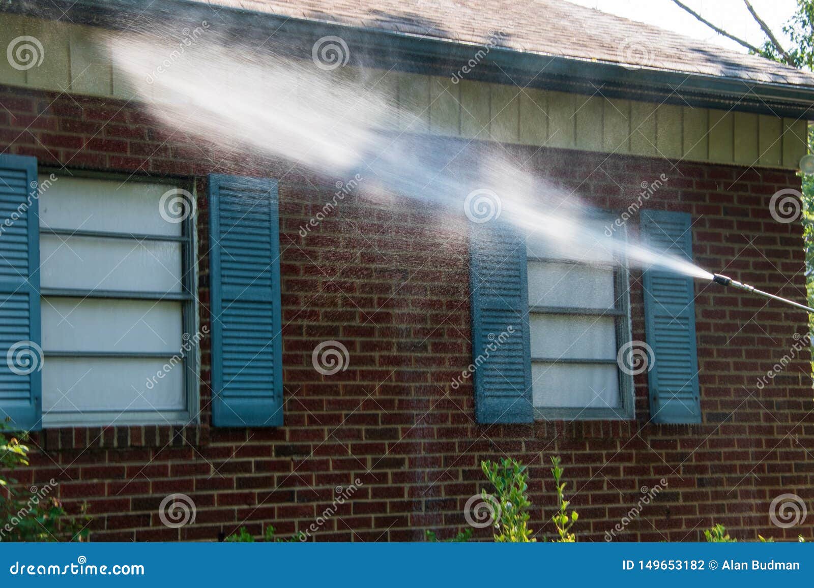 Spray of Water on Siding and Brick Work on the Side of a Building ...