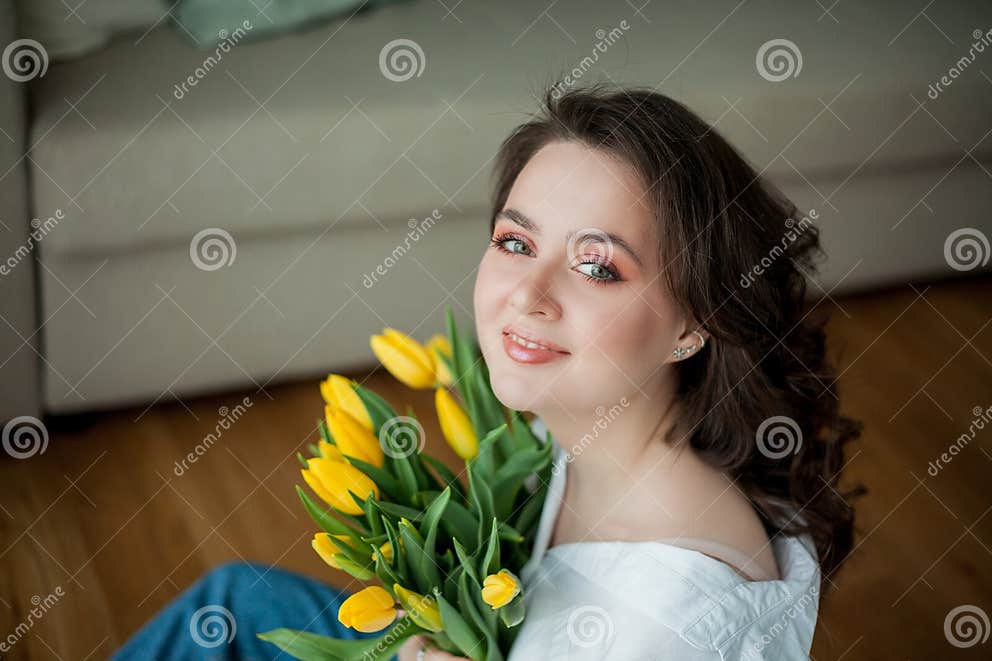 Spring Portrait Of Young Beautiful Woman With Blue Eyes And Curly Hair With Bouquet Of Yellow