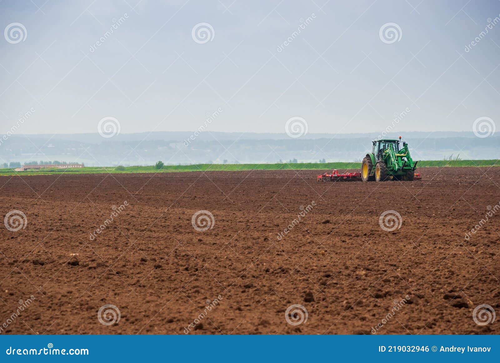 Spring. Sowing Work. A Tractor With A Seeder Trailer Works In The Field ...