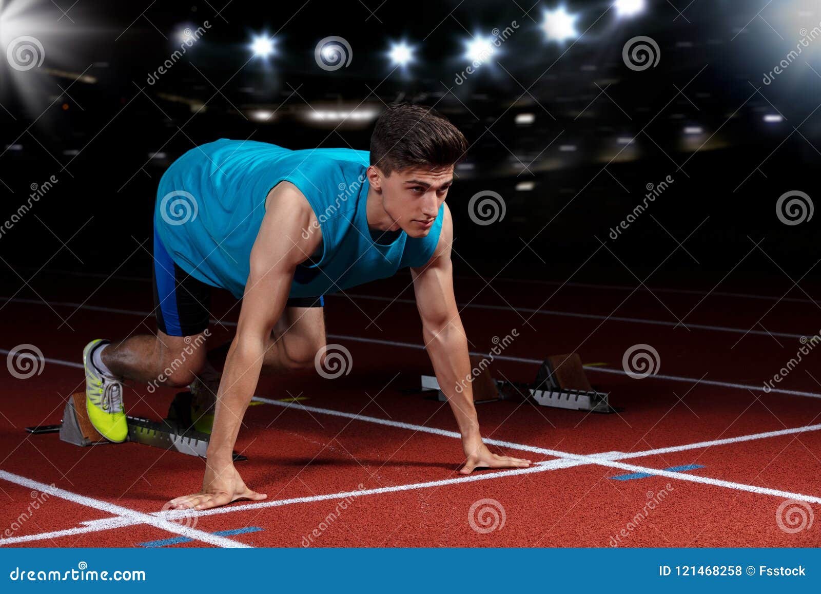Sprinter Leaving Starting Blocks on the Running Track in Front of Big ...