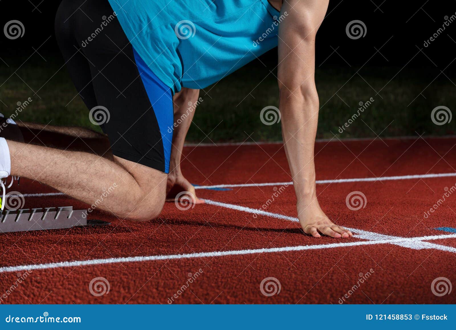 Sprinter Leaving Starting Blocks on the Running Track in Front of Big ...