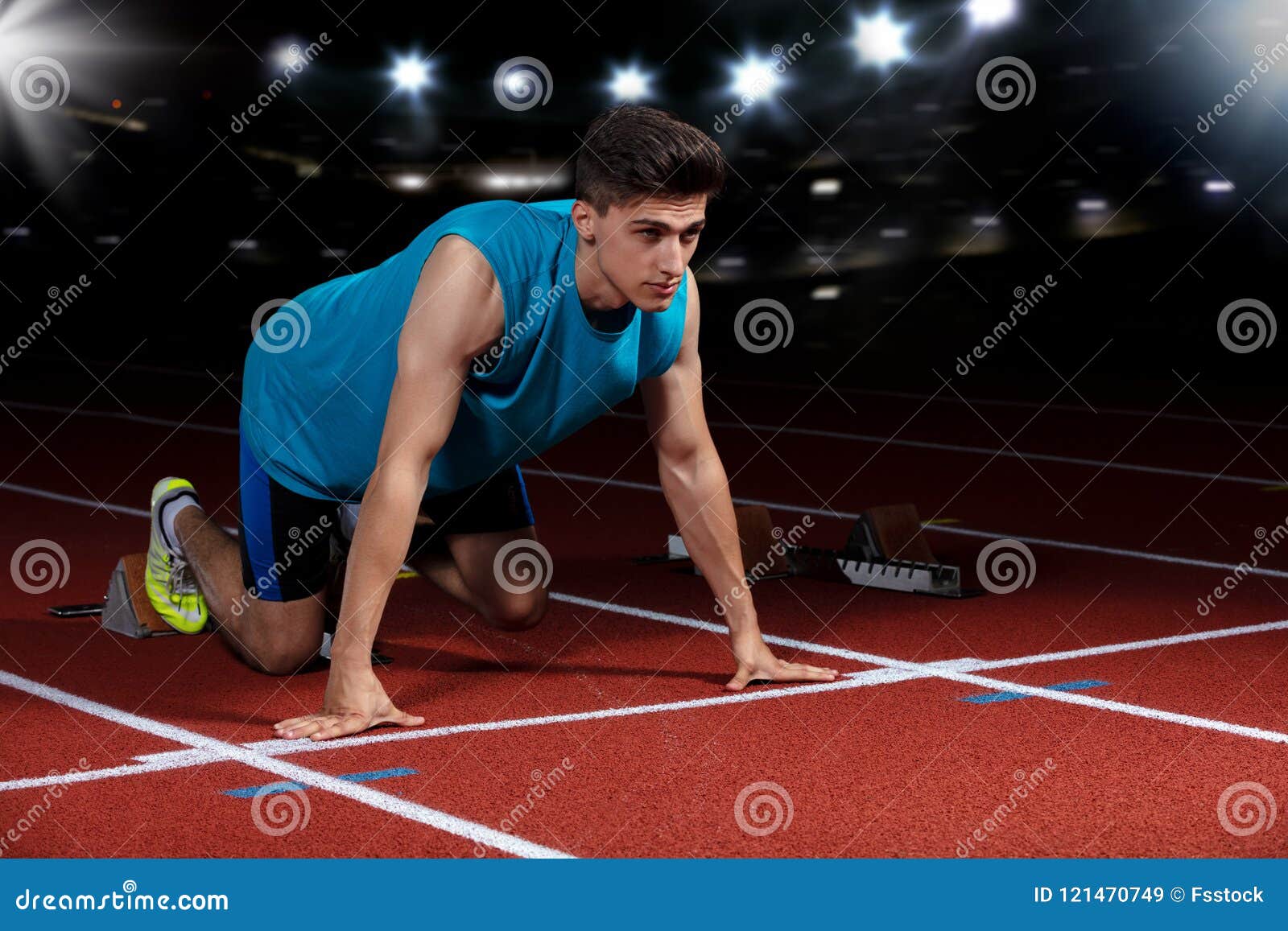 Sprinter Leaving Starting Blocks on the Running Track in Front of Big ...