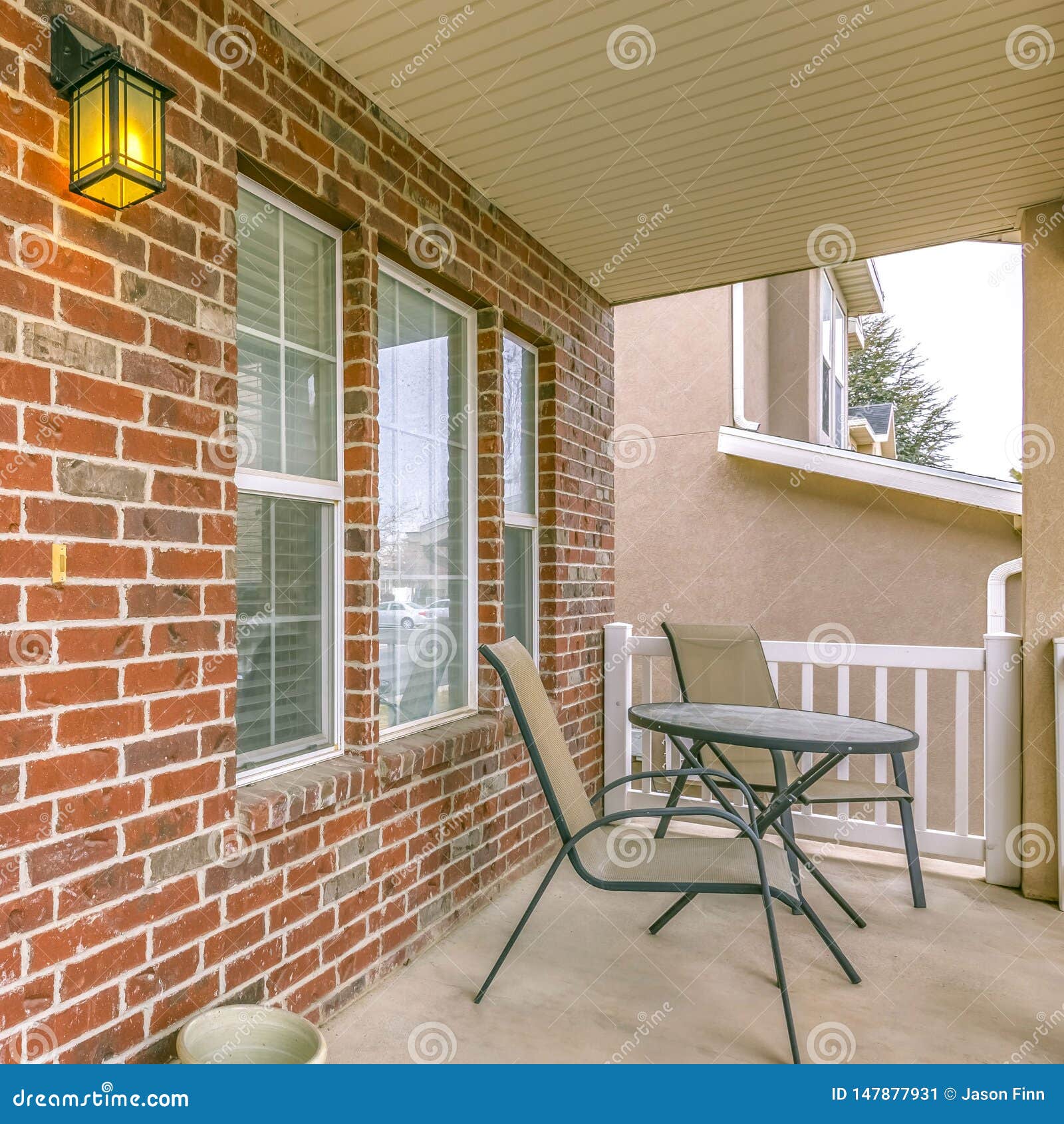 Square Front Porch of a Home with Table and Chairs in Front of Brick ...