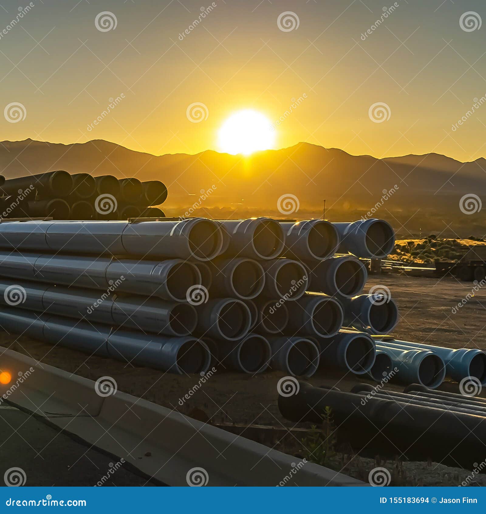 Square Stack of Pipes with a Golden Sun Setting Behind a Mountain in ...
