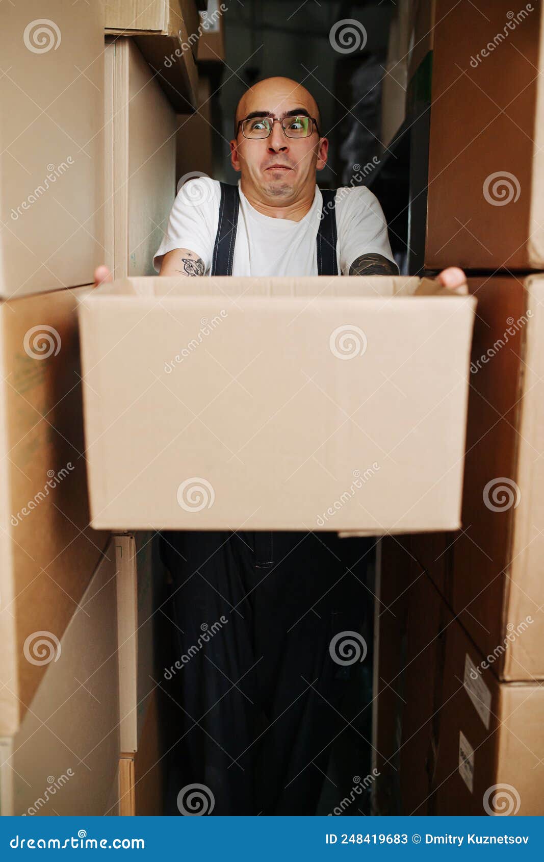 Squeezed Male Warehouse Worker Carrying a Box between High Stacks of ...