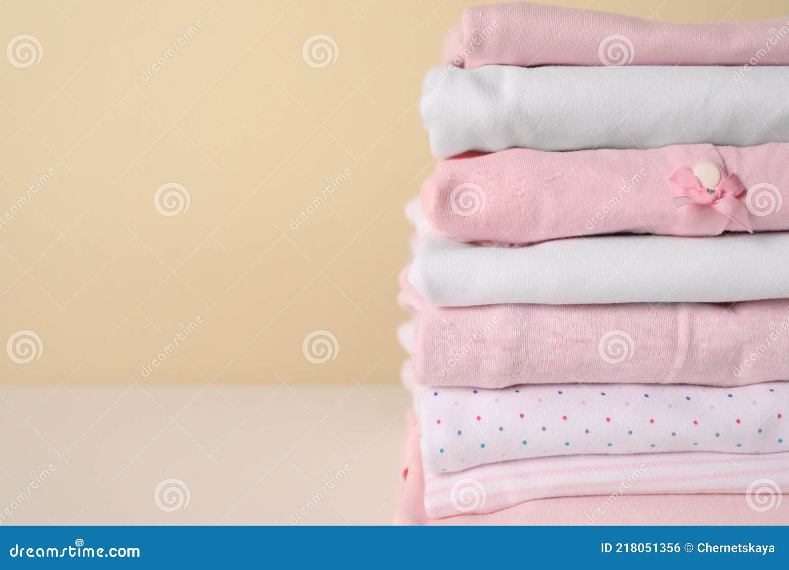 Stack of Baby Girl`s Clothes on White Table, Closeup. Space for Text ...