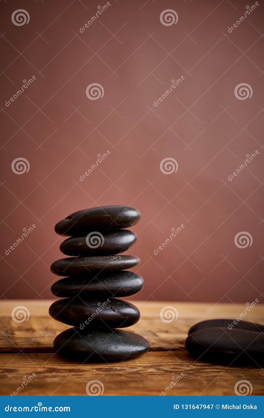 Stack of Black Spa Stones for Massage on a Brown Background and an ...
