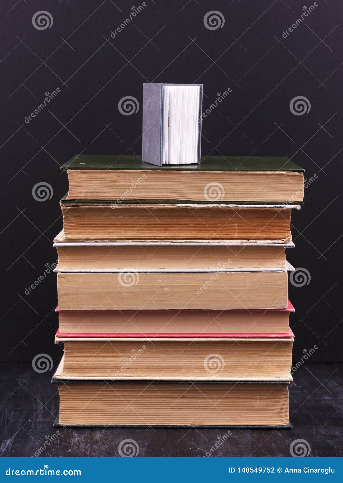 Stack of Books on a Black Background with Small Book on Top Stock Photo ...