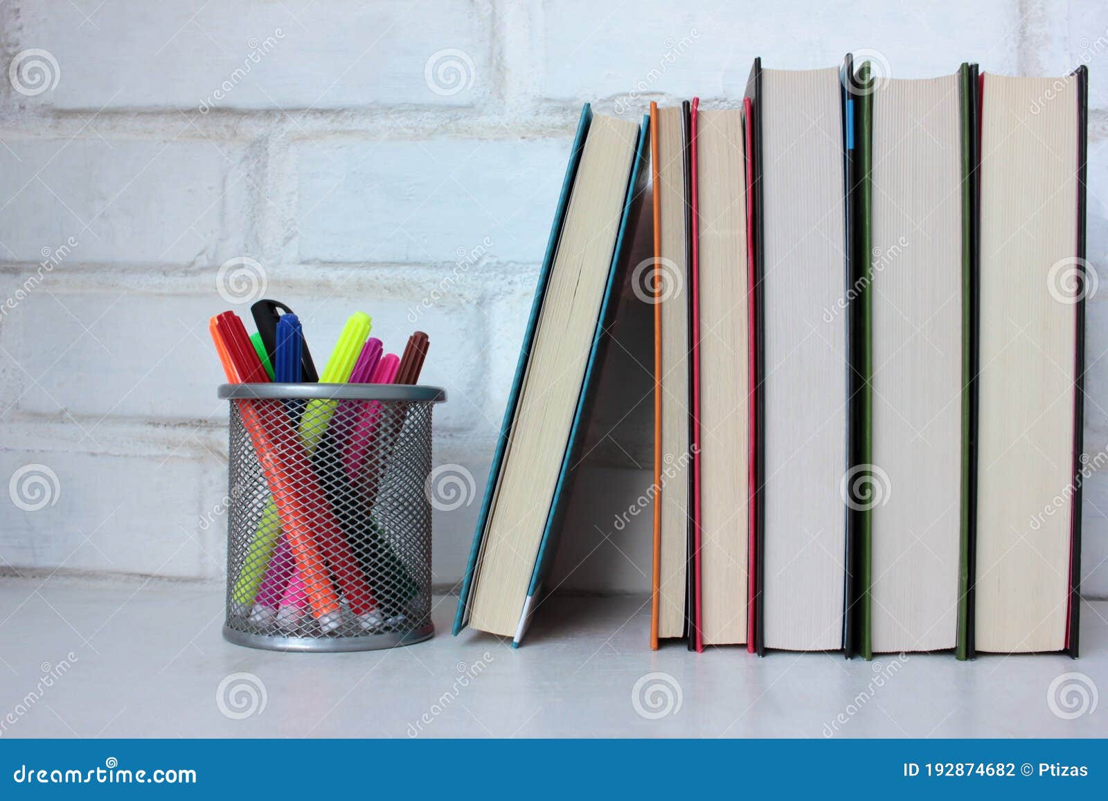 Stack of Books and Felt-tip Pens on the Table Against White Brick Wall ...