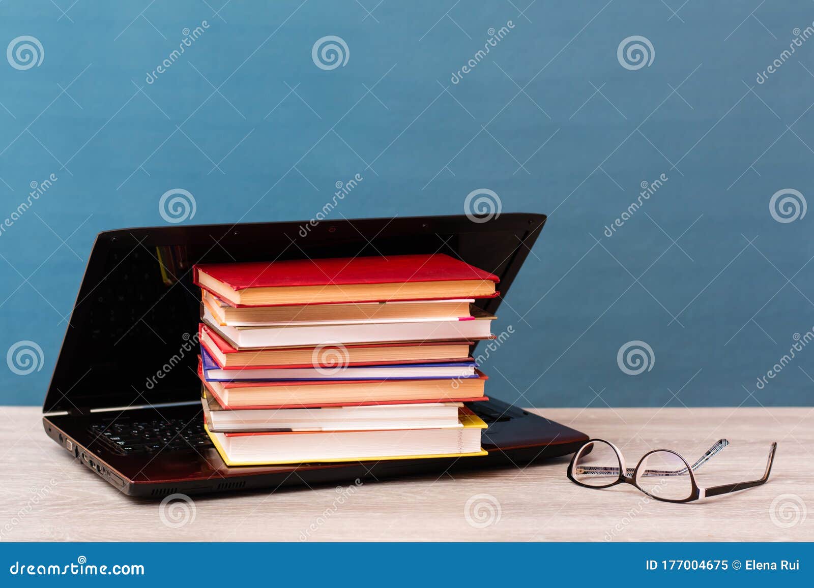 A Stack of Books Lies in an Open Laptop and Glasses on the Table ...