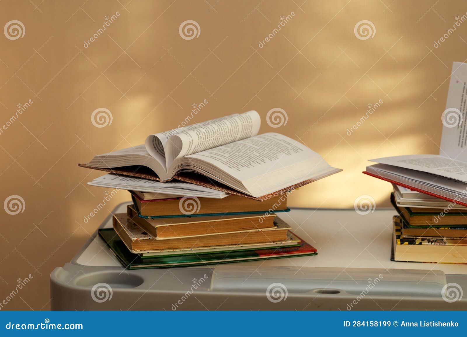 Stack of Books with an Open Book with Curved Pages Lies on the Office ...