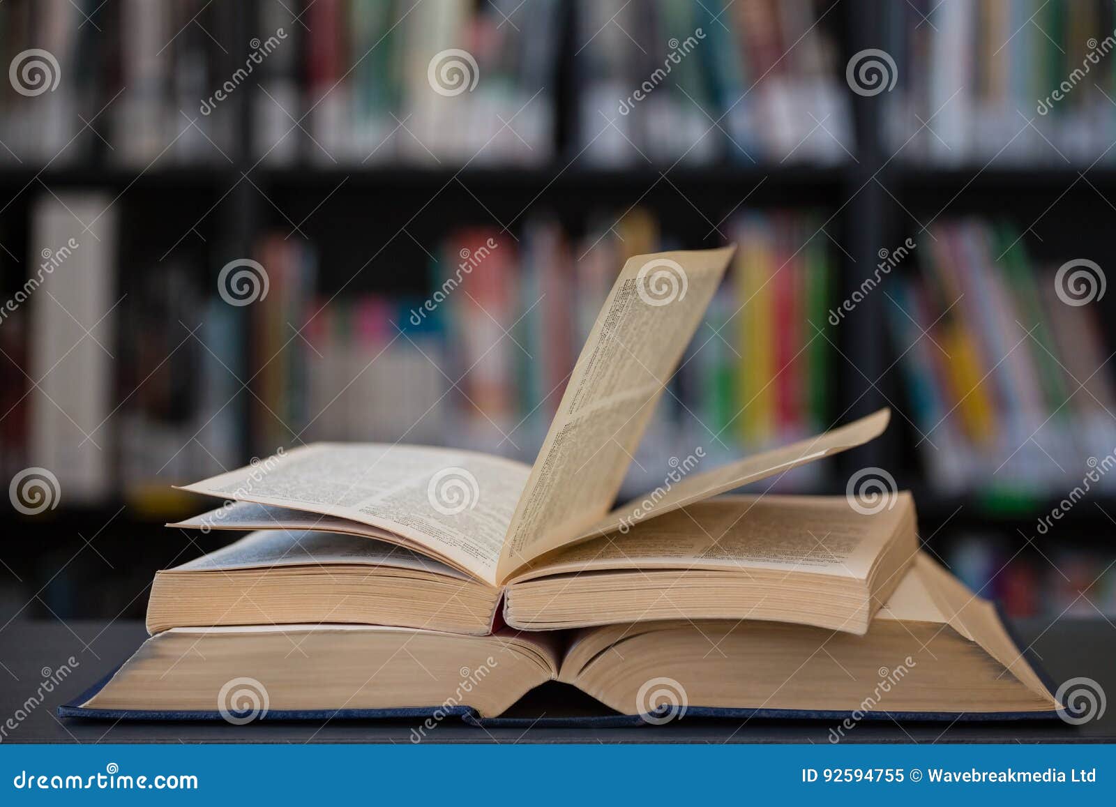 Stack of Books on Table Against Shelf Stock Image - Image of sunlight ...