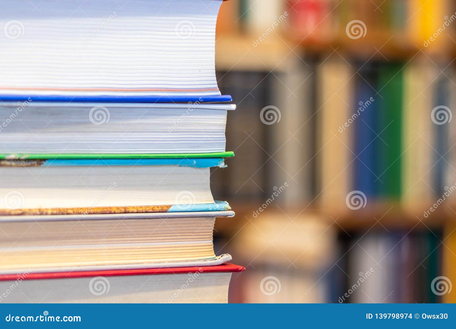 A Stack of Books on the Table on the Background of Bookshelves Stock ...