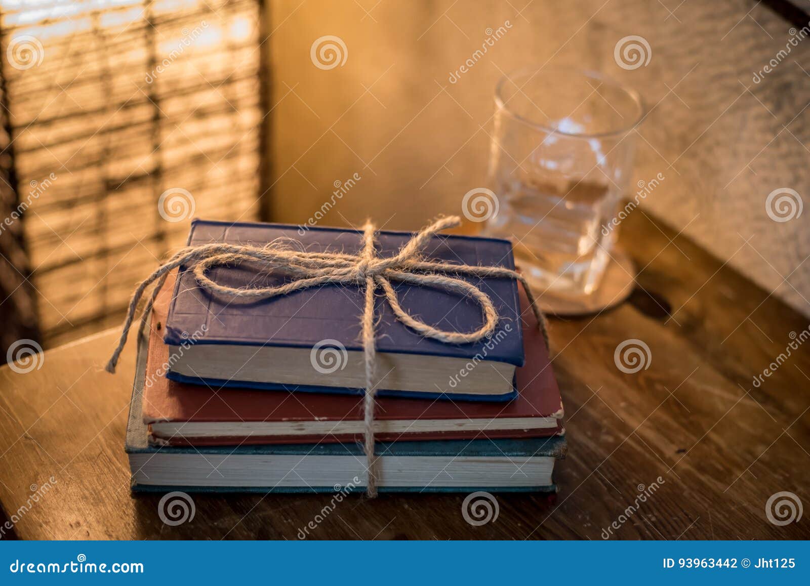 Stack of Books Tied with a String with a Glass of Water in Background ...
