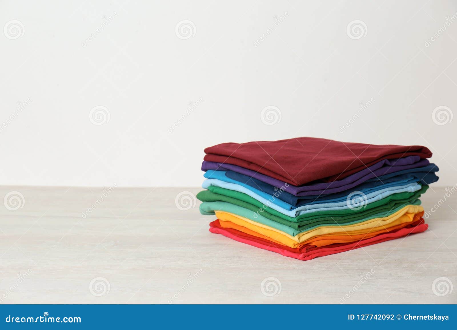 Stack of Bright Folded Clothes on Table Against White Background Stock ...
