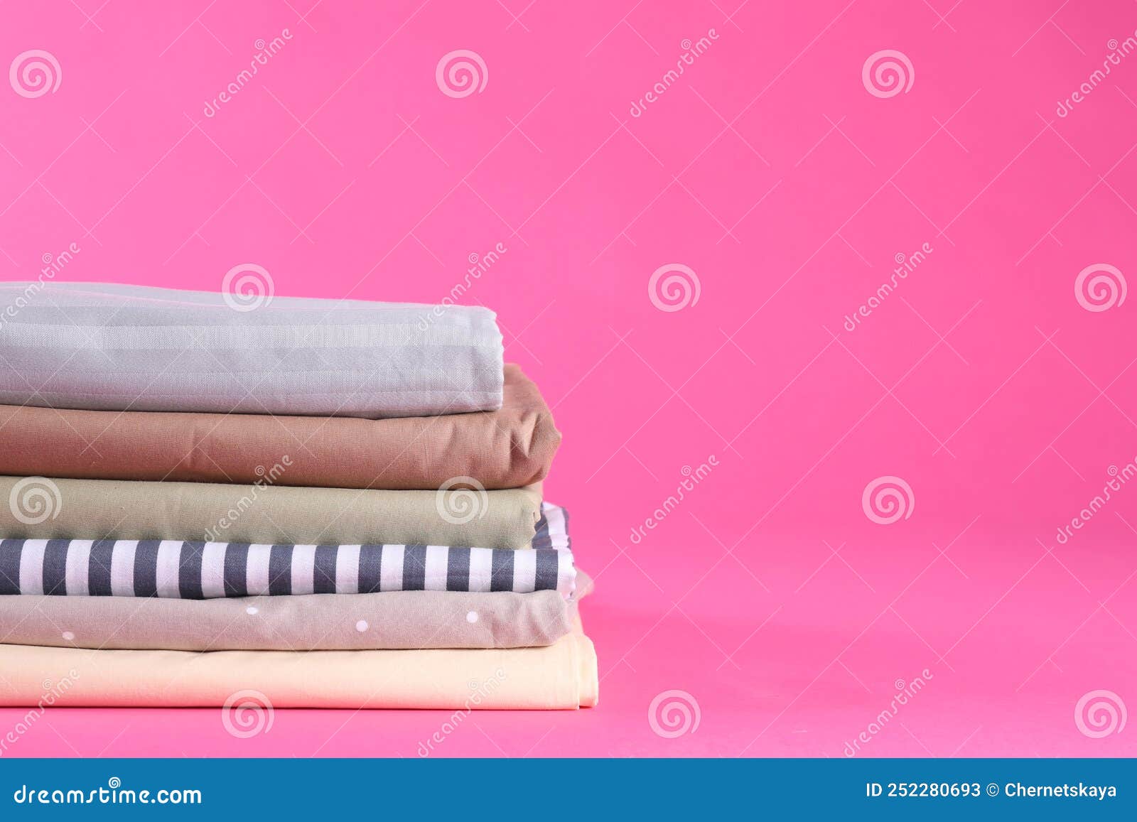 Stack of Clean Bed Sheets on Pink Background. Space for Text Stock ...