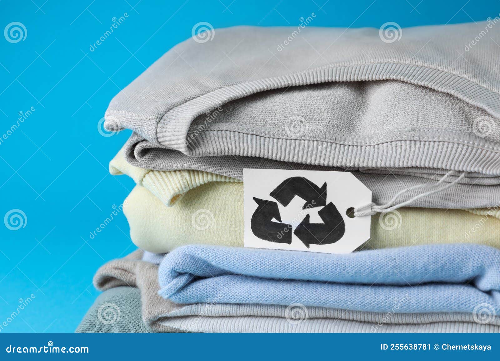 Stack of Clothes with Recycling Label on Light Blue Background, Closeup ...