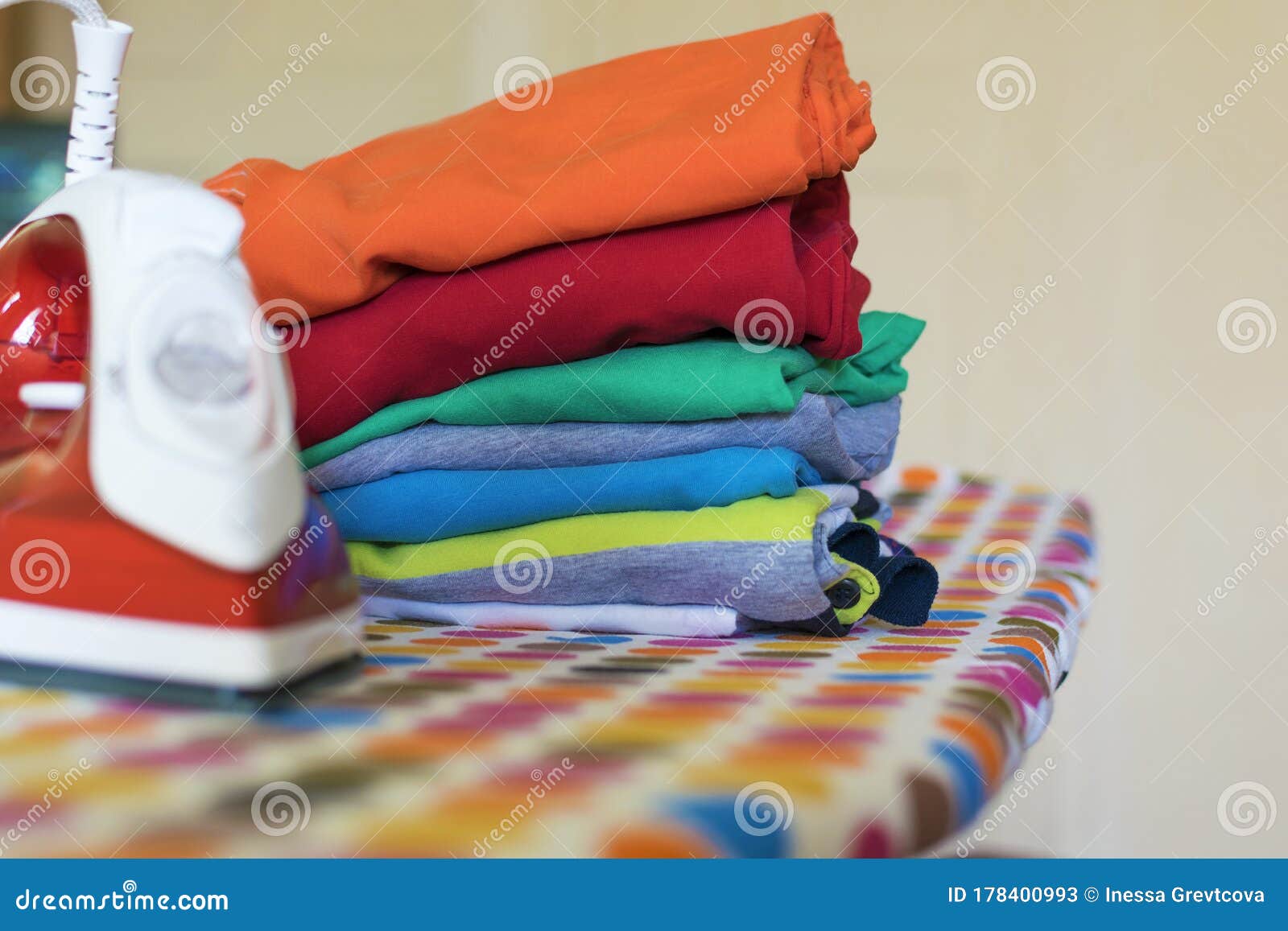 A Stack of Clothes and a Red and White Iron on the Ironing Board. Stock ...