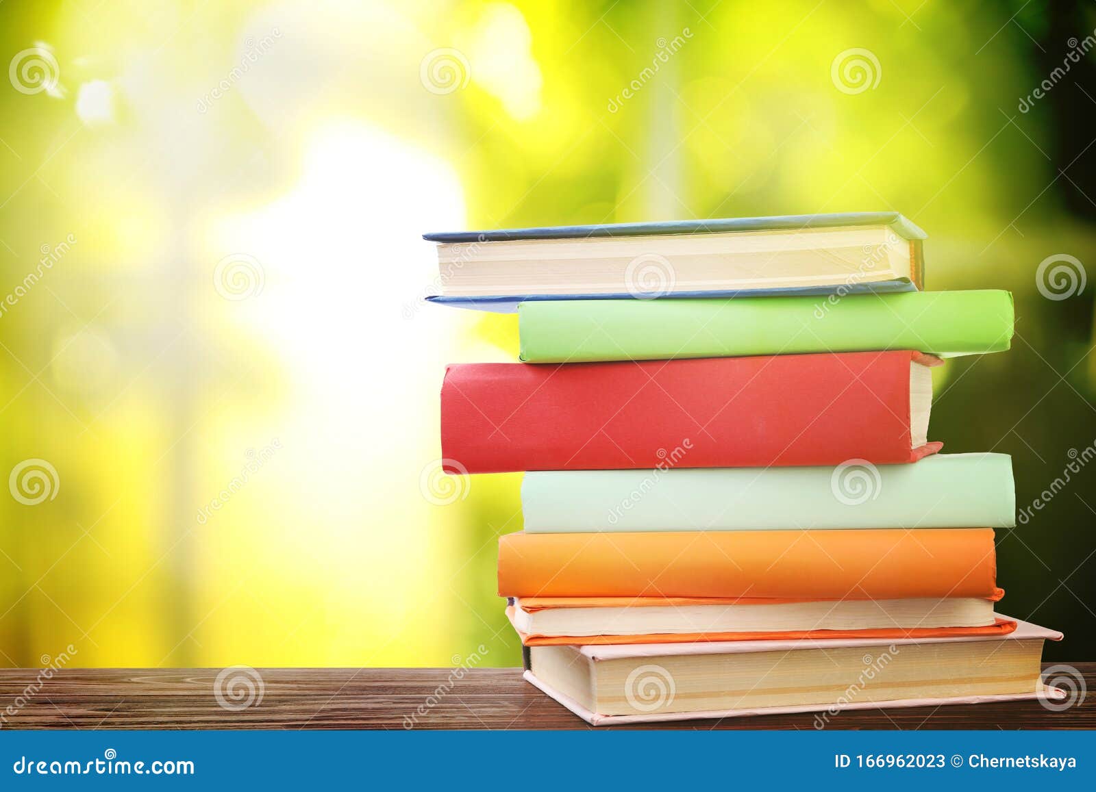 Stack of Colorful Books on Wooden Table Against Green Background. Space ...