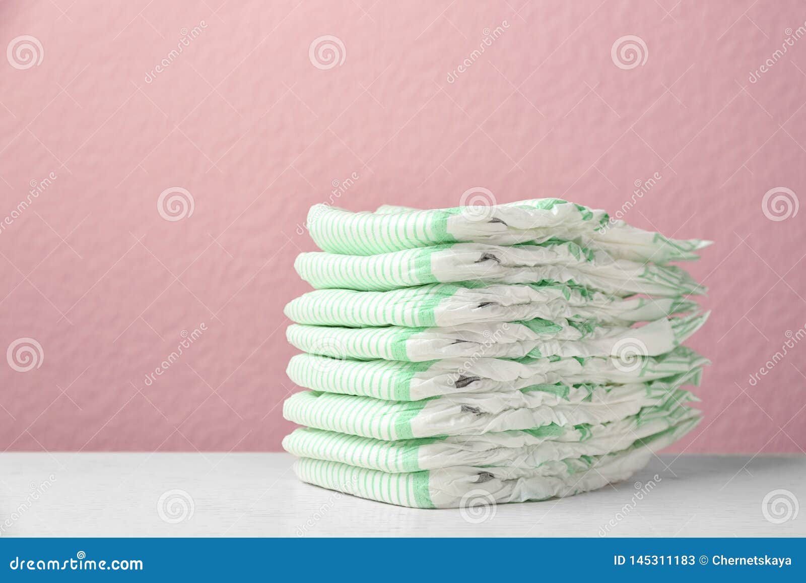 Stack of Diapers on Table Against Color Background. Baby Accessories ...