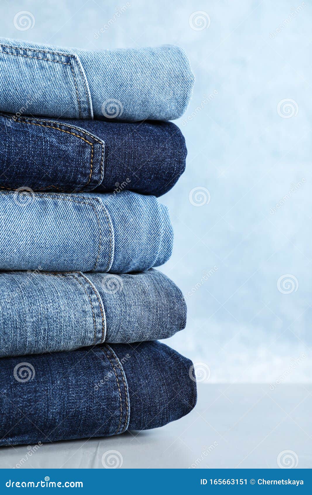 Stack of Different Jeans on Light Table Against Blue Background Stock ...