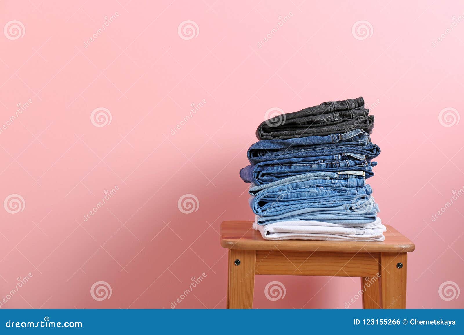 Stack of Different Jeans on Stool Against Color Stock Photo - Image of ...